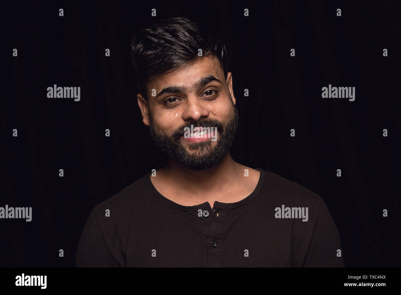 Close up portrait of young man isolated on black studio background ...
