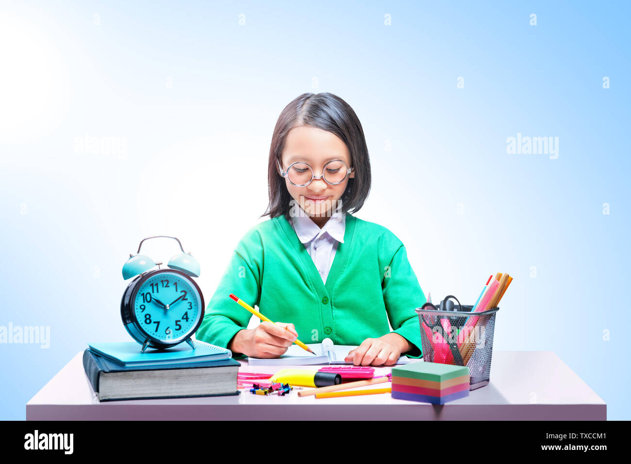 Asian cute girl in glasses learning with school stationary on the desk ...