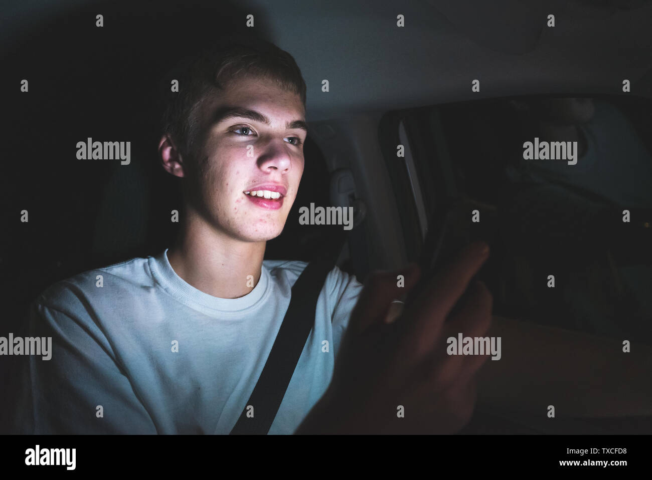 Distracted teenager driving a car with his cell phone in his hand. The ...