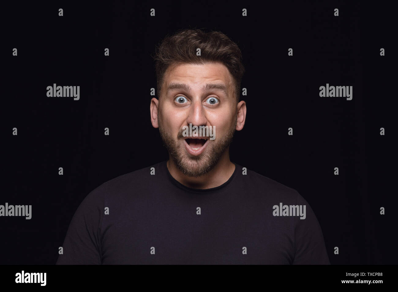 Close up portrait of young man isolated on black studio background ...