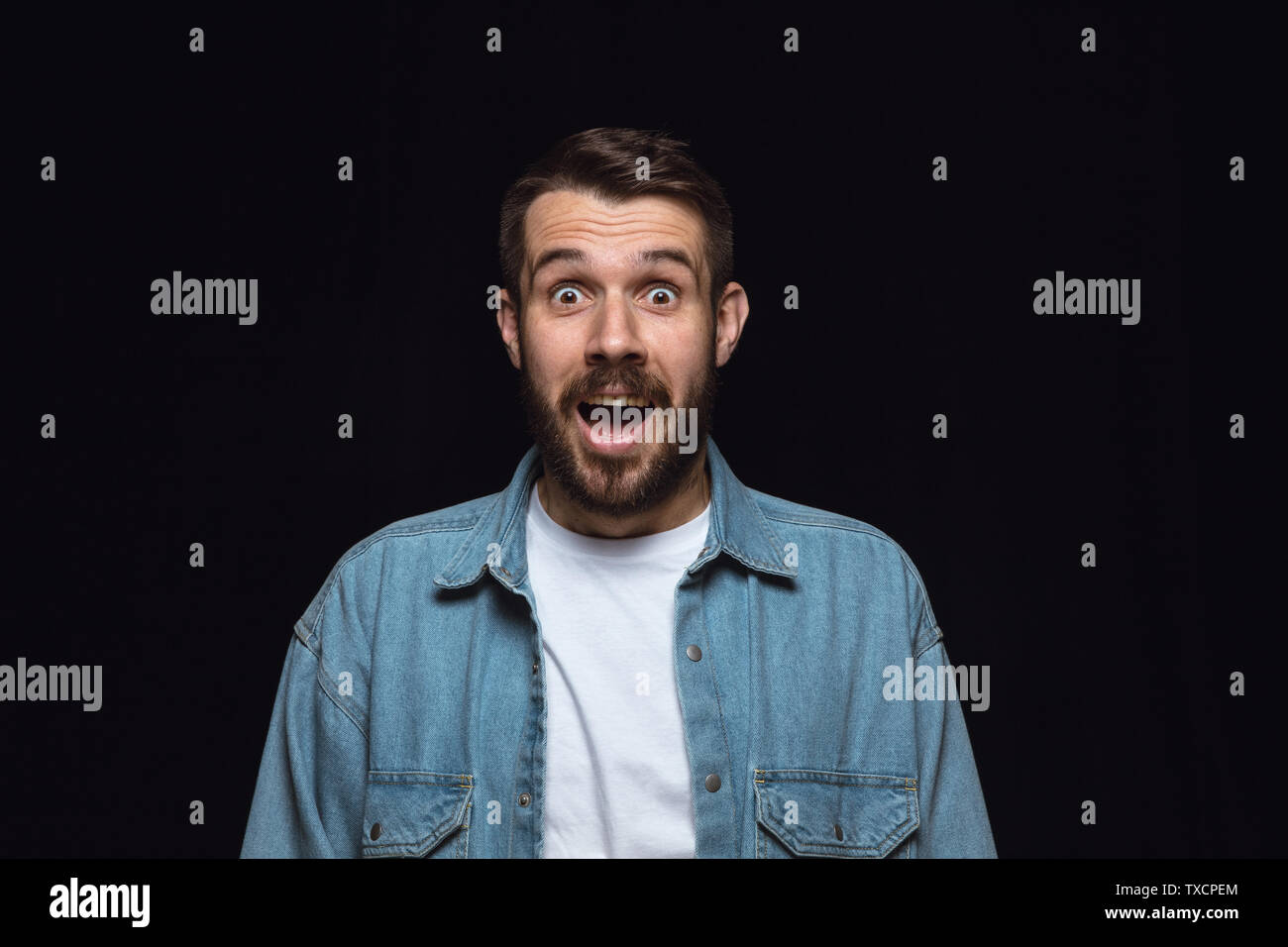Close up portrait of young man isolated on black studio background ...
