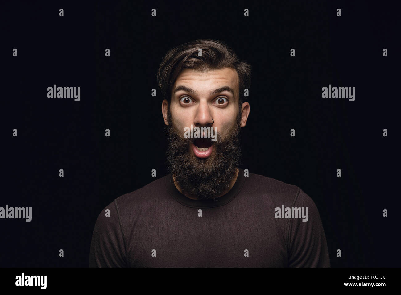 Close up portrait of young man isolated on black studio background ...