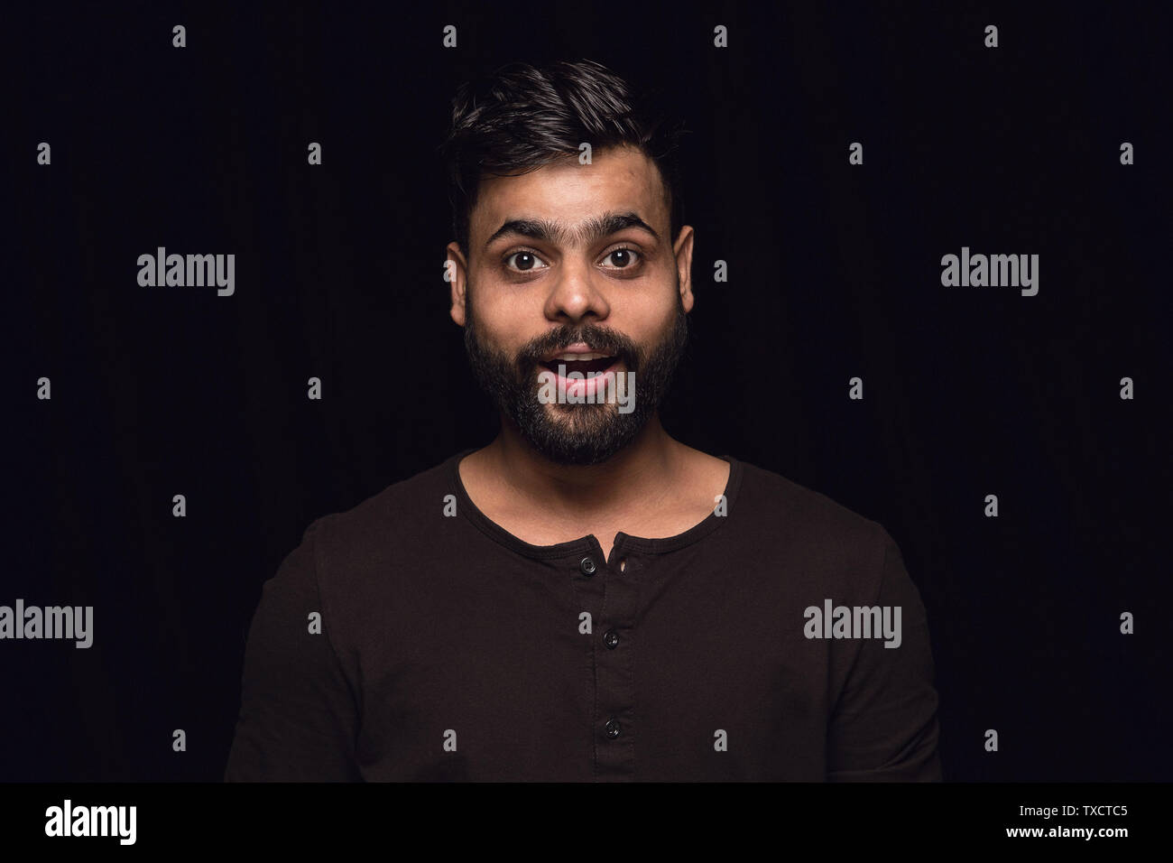 Close up portrait of young man isolated on black studio background ...