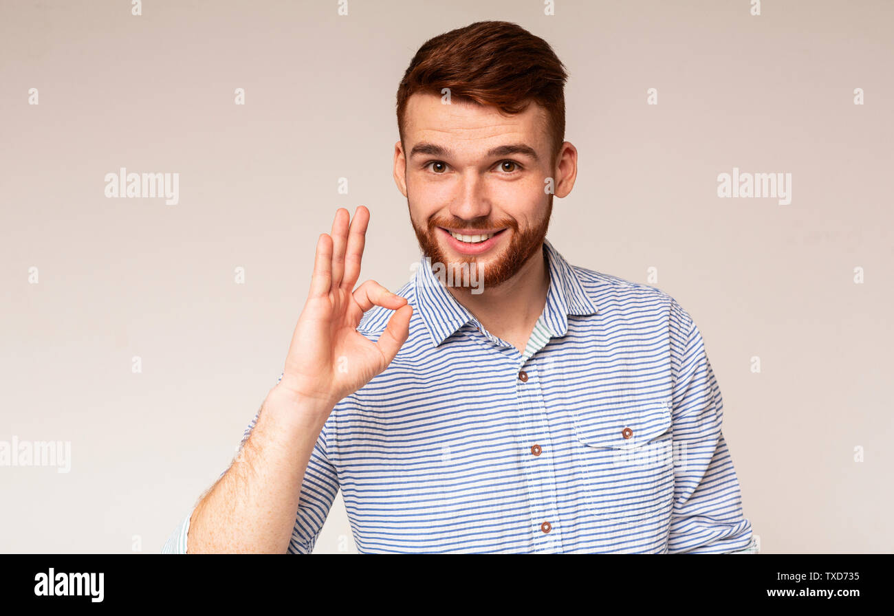 It is ok. Hansome guy showing gesture and smiling on studio background ...