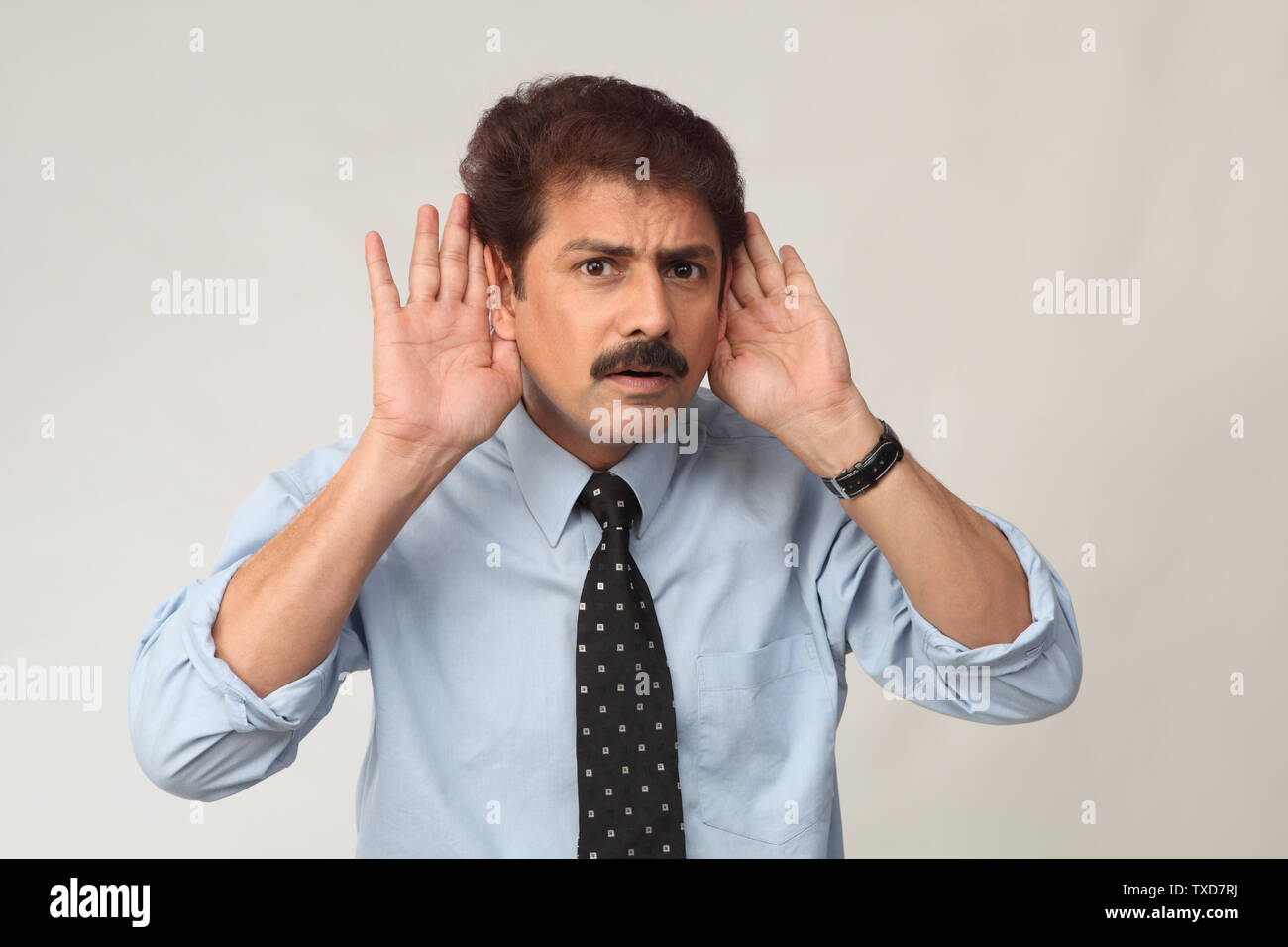 Portrait of a businessman cupping hands to ears Stock Photo - Alamy