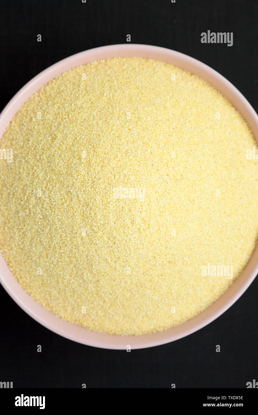 Dry semolina durum flour in a pink bowl over black background, view ...