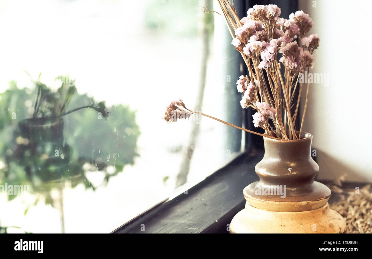 A small plant pot displayed in the window. Bouquet of flowers near ...