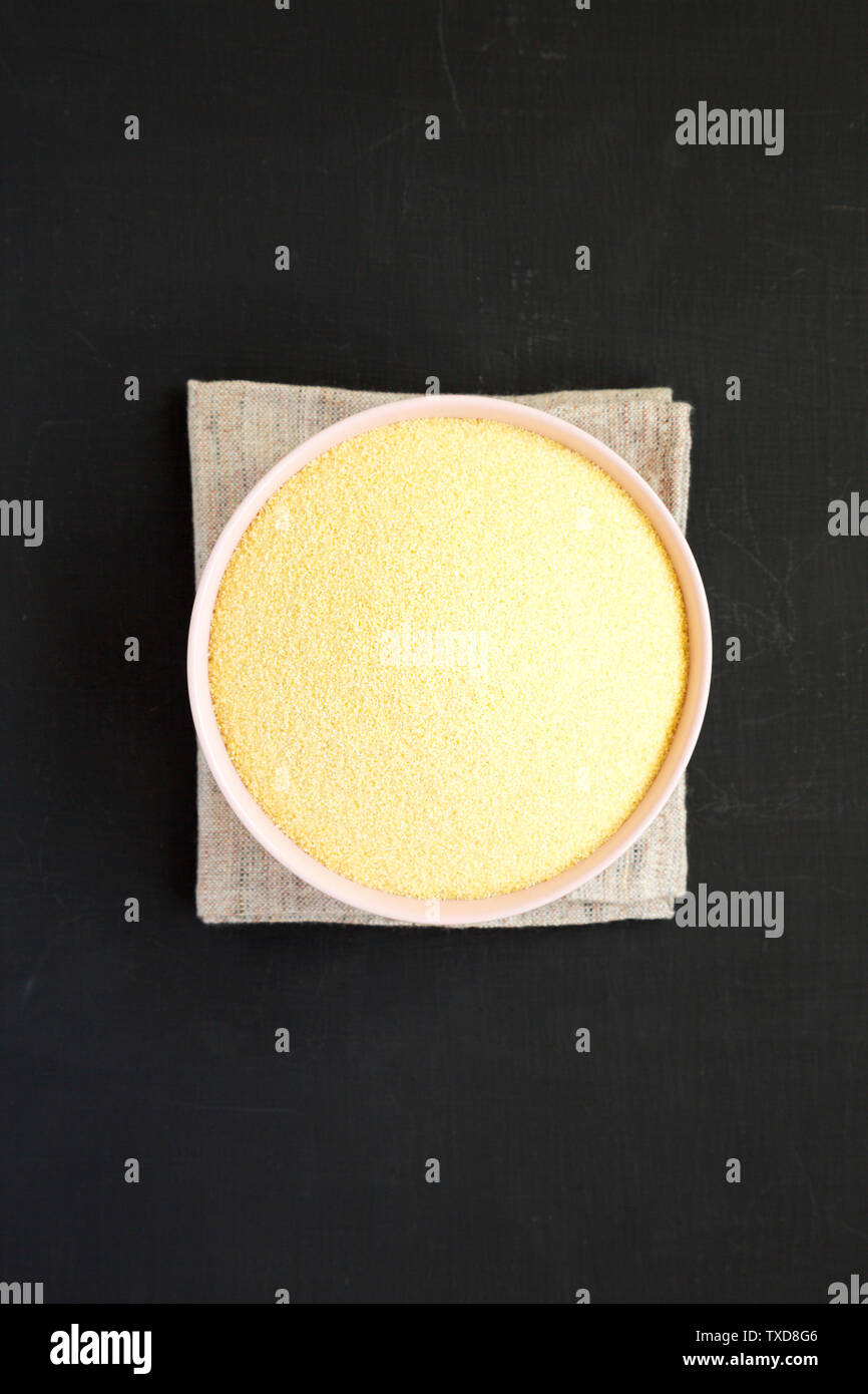 Dry semolina durum flour in a pink bowl over black surface, top view ...