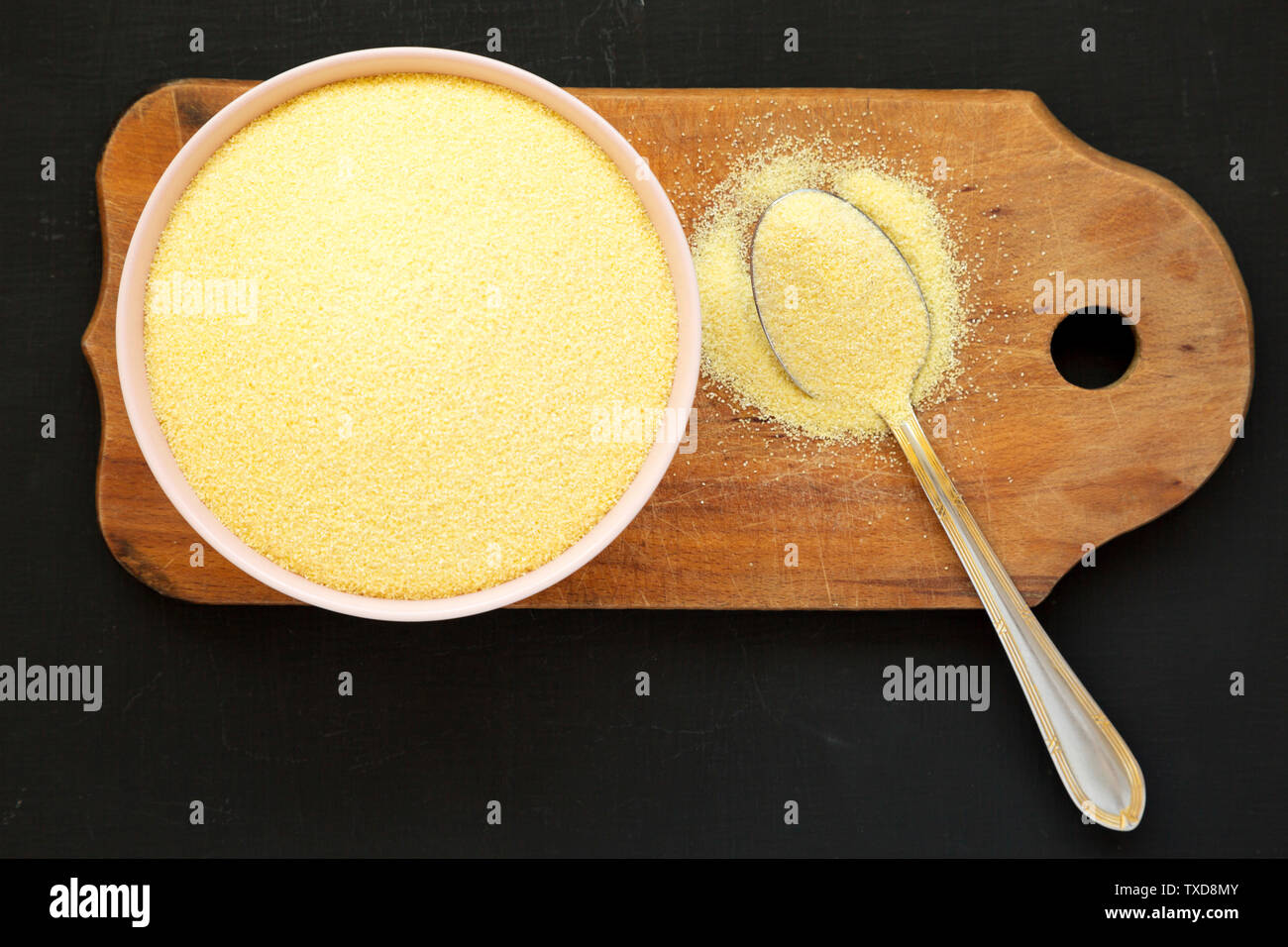 Dry semolina durum flour in a pink bowl over black surface, top view ...
