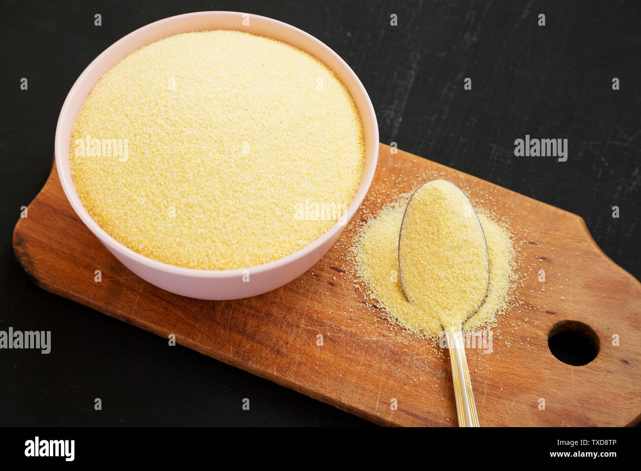 Dry semolina durum flour in a pink bowl over black background, side ...