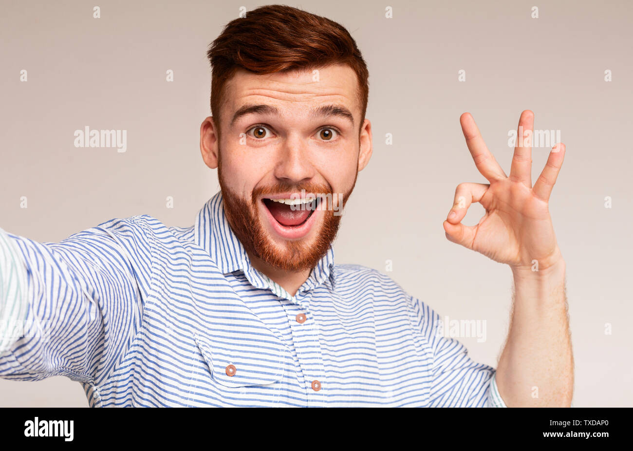 Happy millennial guy showing OK sign on camera and making selfie ...