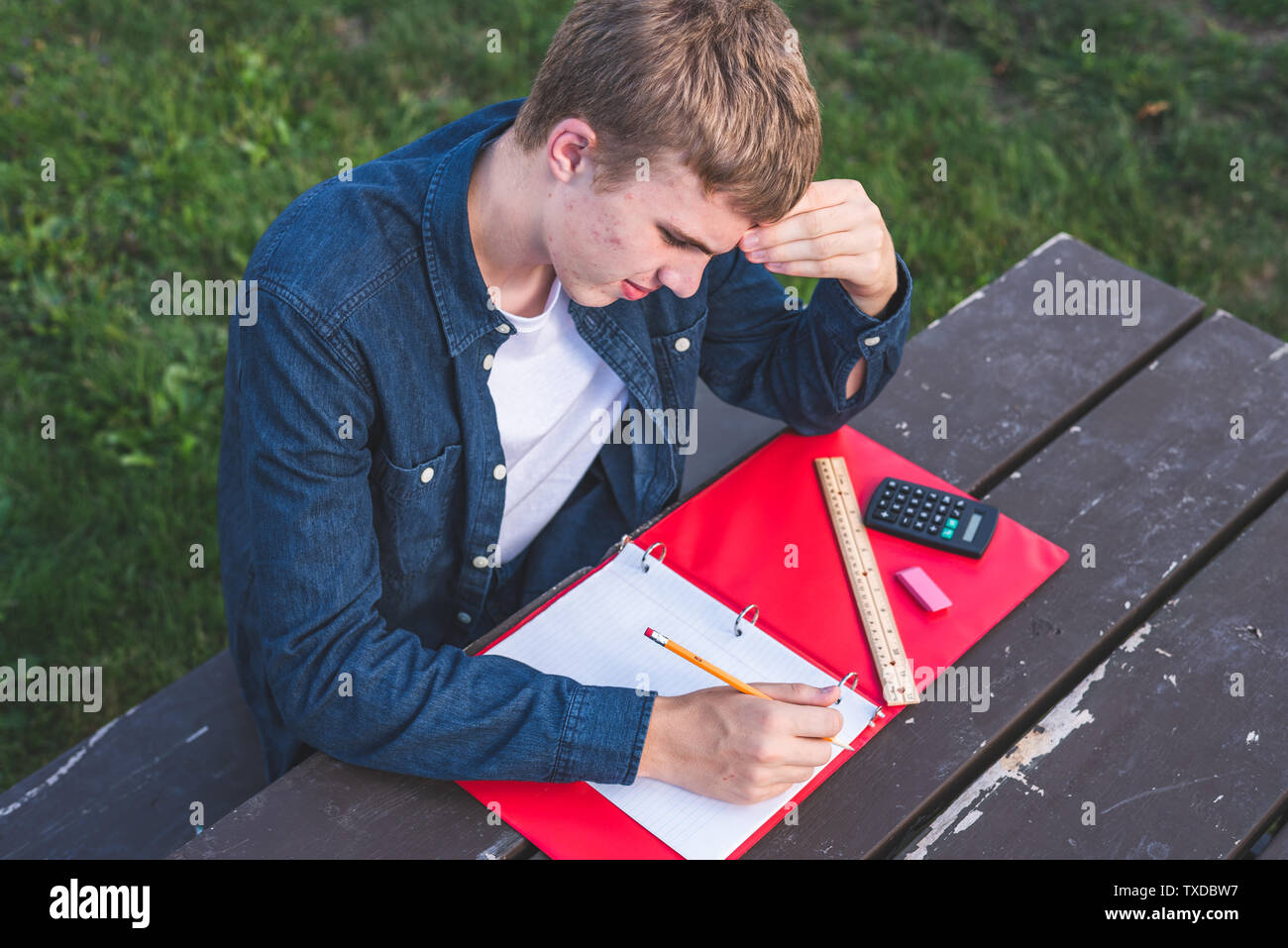 Confused teenager doing his homework alone in a park Stock Photo - Alamy
