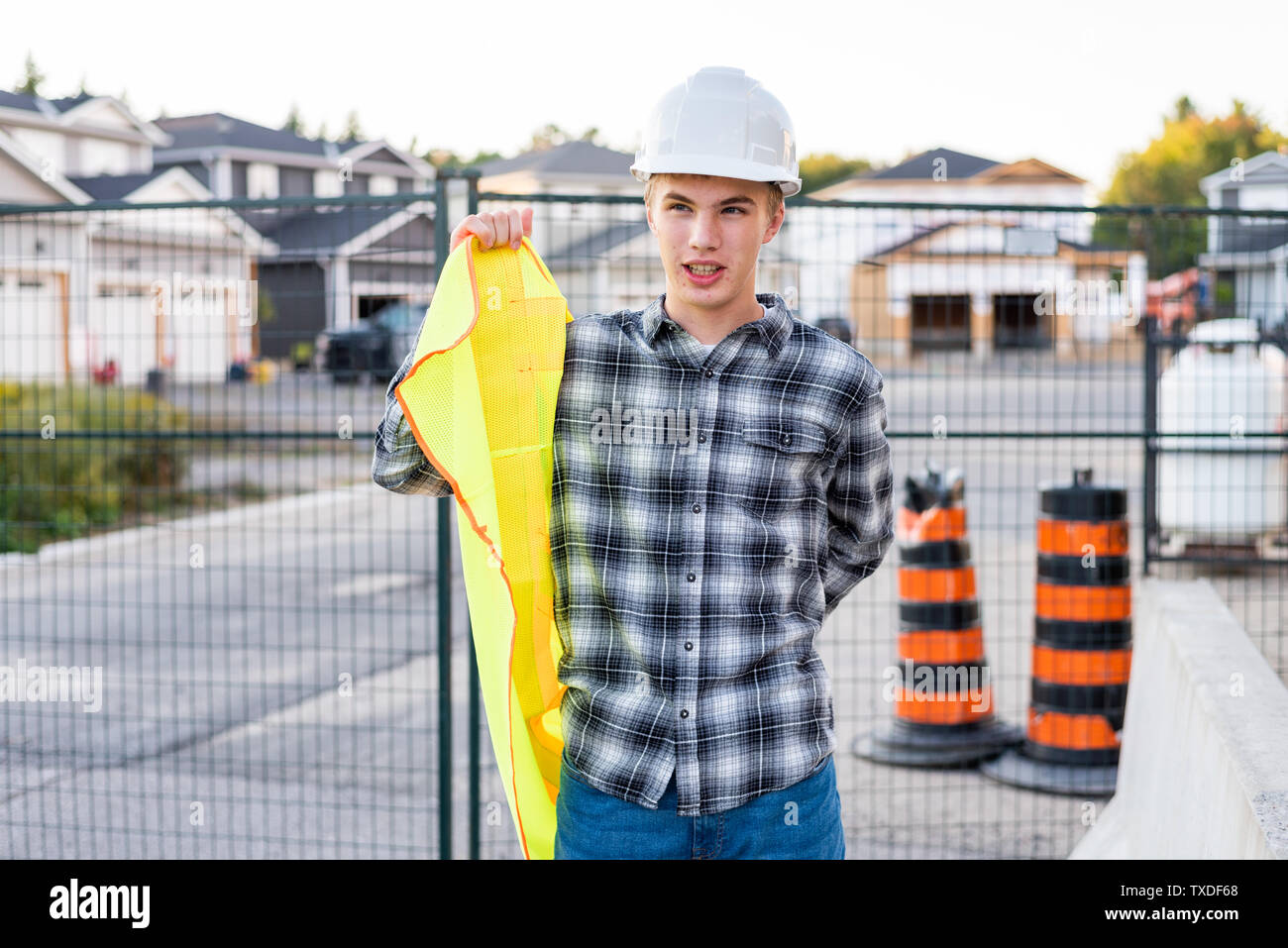 Young construction worker putting on his safety gear at a job site ...