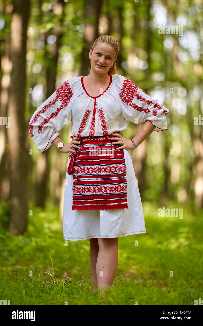 Portrait of a Romanian girl in traditional costume in an oak forest ...