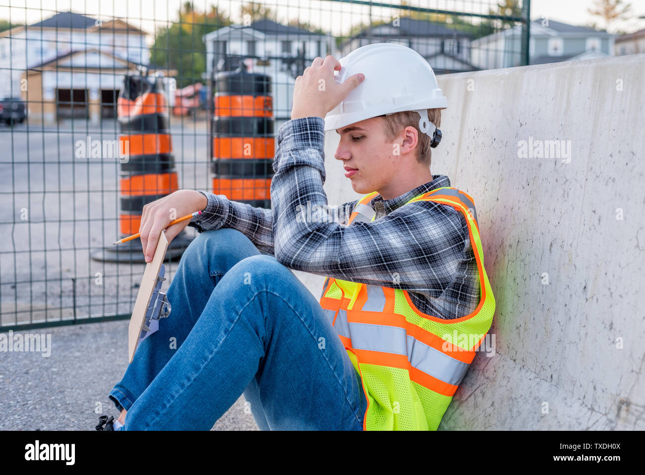 Upset and frustrated construction worker sitting down at a job site ...