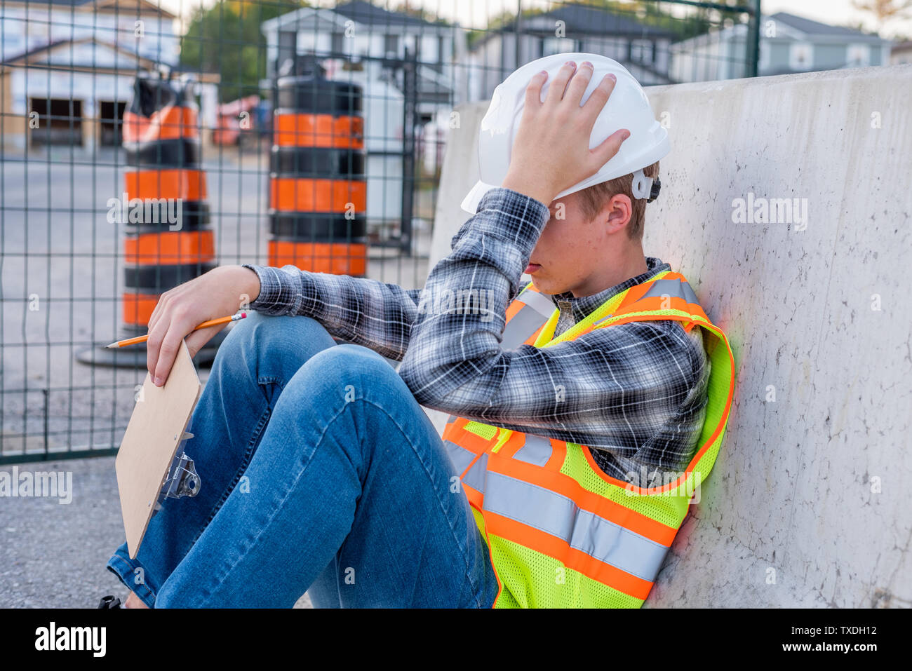 Upset and frustrated construction worker sitting down at a job site ...