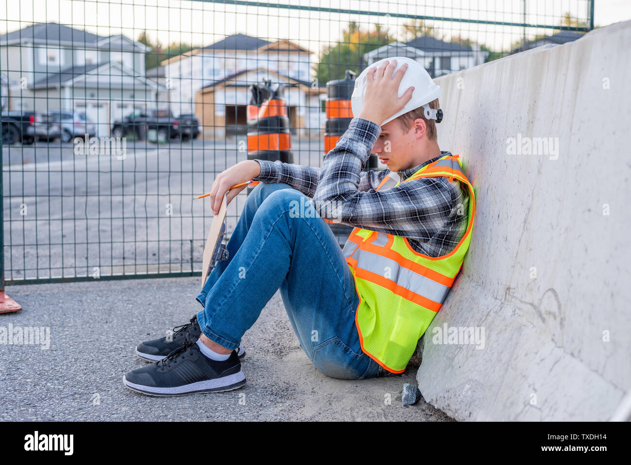 Upset and frustrated construction worker sitting down at a job site ...