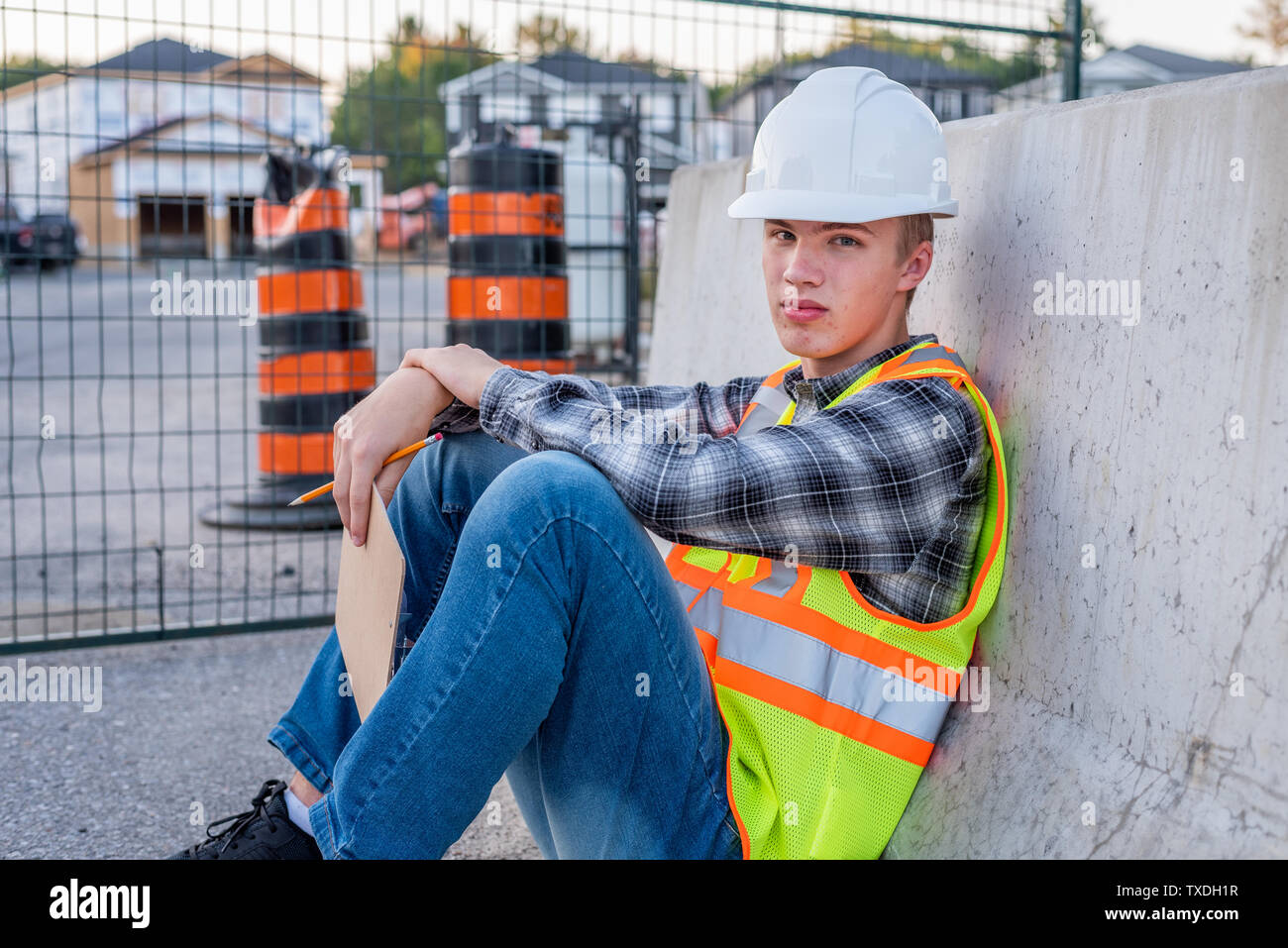 Upset and frustrated construction worker sitting down at a job site ...