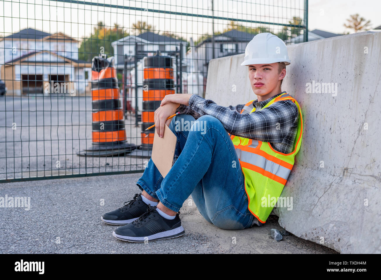 Upset and frustrated construction worker sitting down at a job site ...