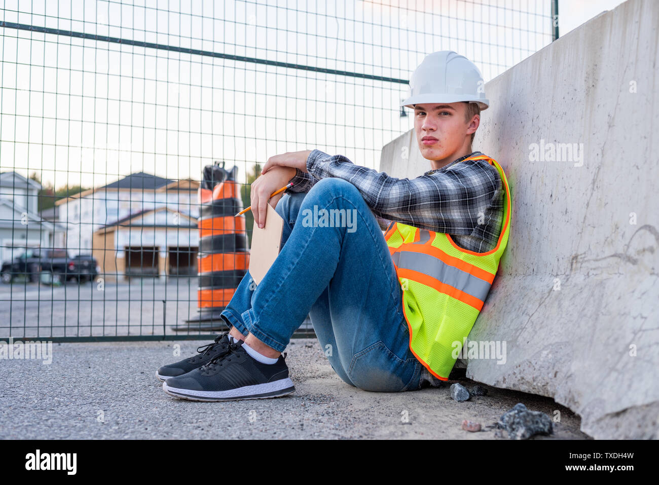 Upset and frustrated construction worker sitting down at a job site ...