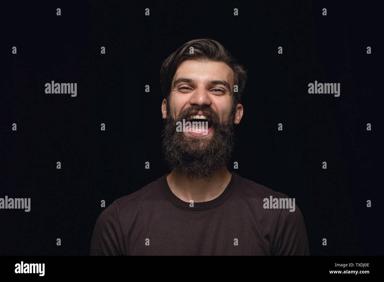 Close up portrait of young man isolated on black studio background ...