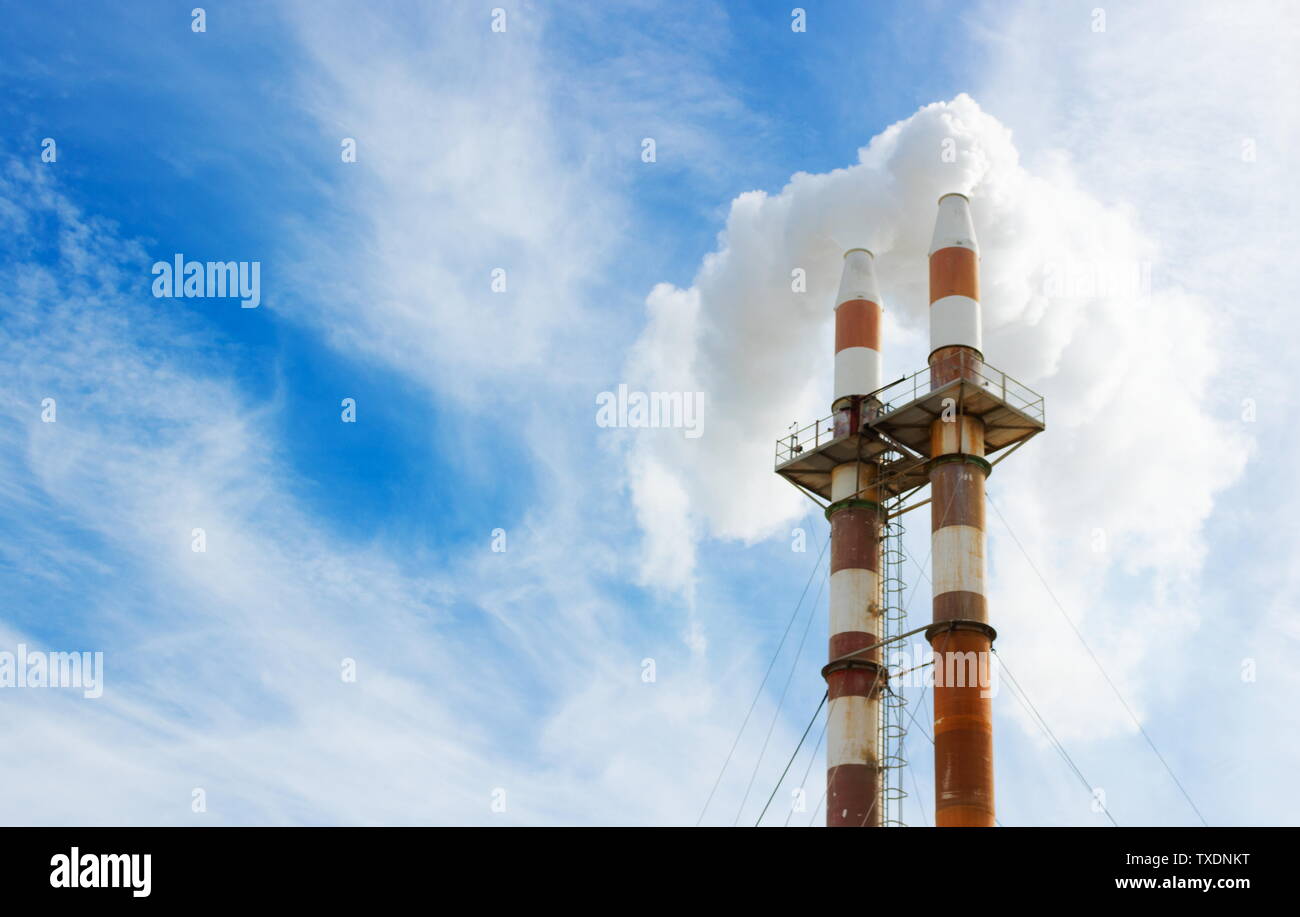 Close up image of two smoke stacks billowing smoke into the atmosphere ...