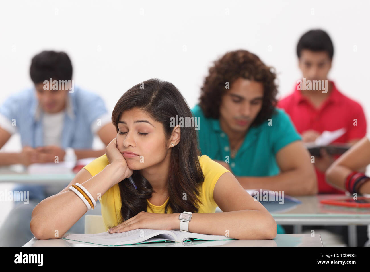 Female college student napping in classroom with her classmates in the ...