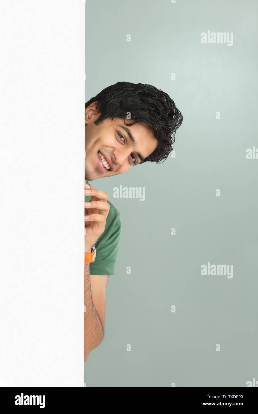 Portrait of a man hiding behind a placard and smiling Stock Photo - Alamy