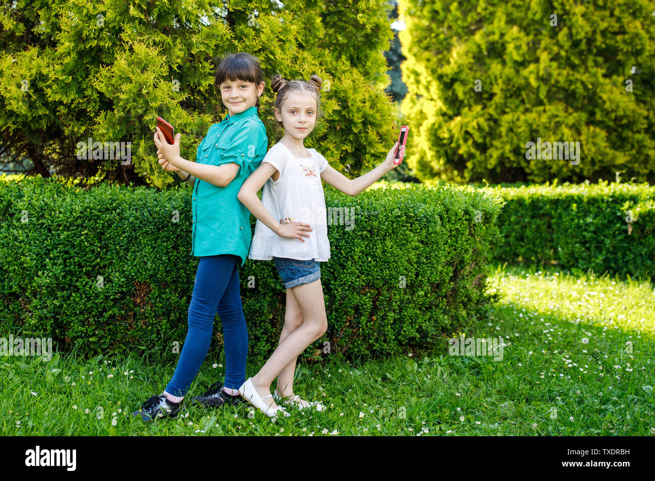 Two cute girls of school age photograph themselves on the phone near ...