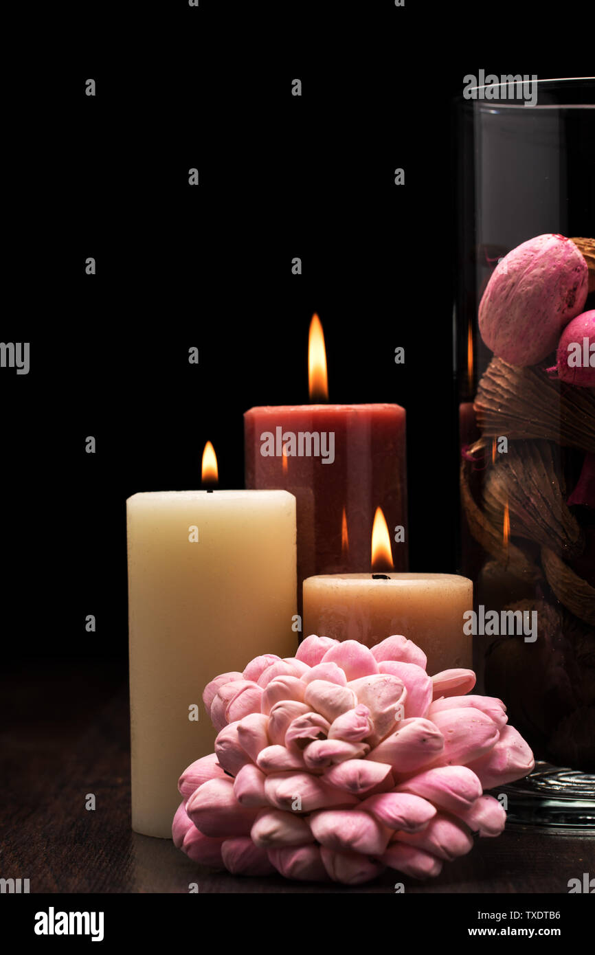 Glass filled with brown, pink and red potpourri with three lit candles ...