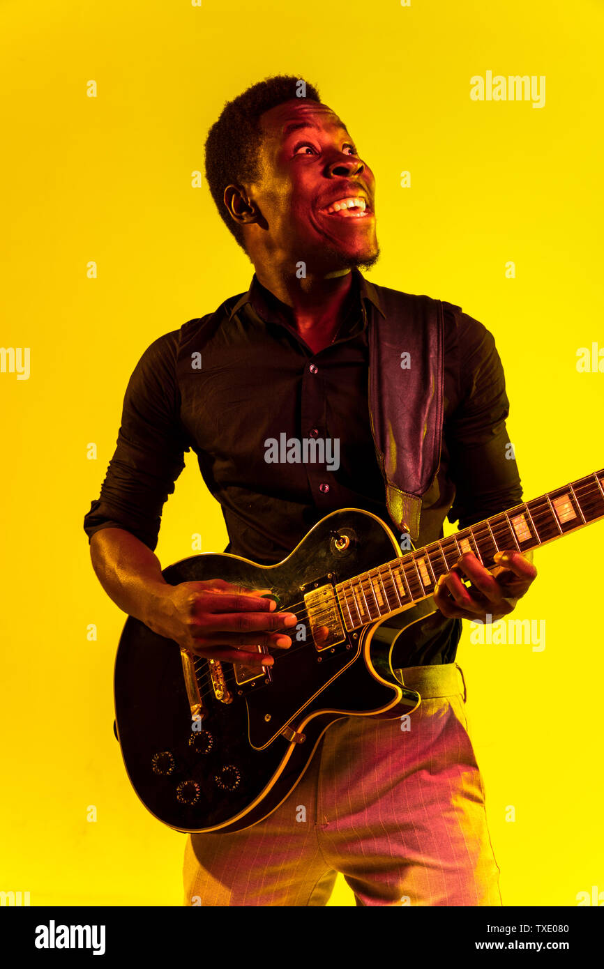 Young african-american musician playing the guitar like a rockstar on ...