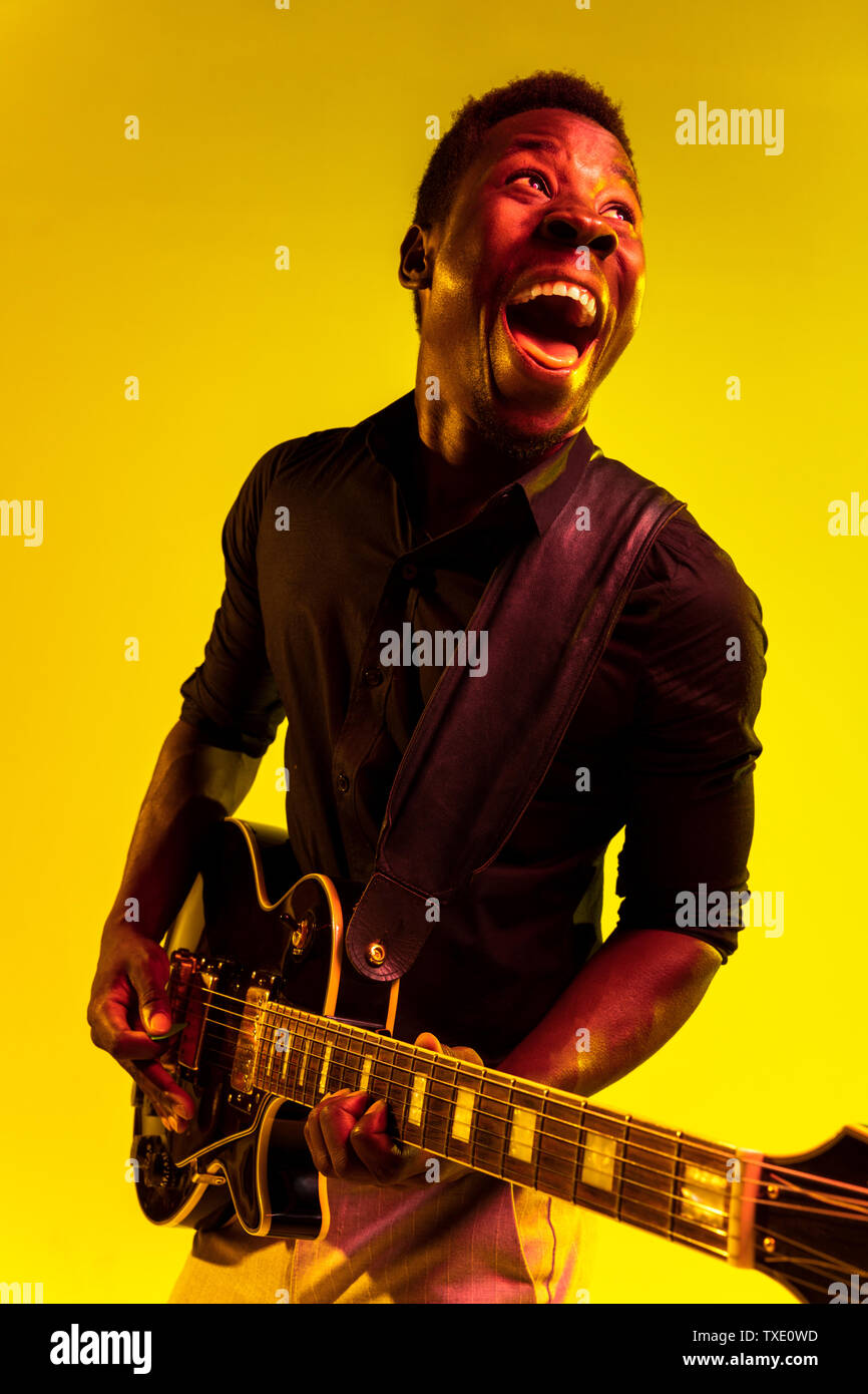 Young african-american musician playing the guitar like a rockstar on ...