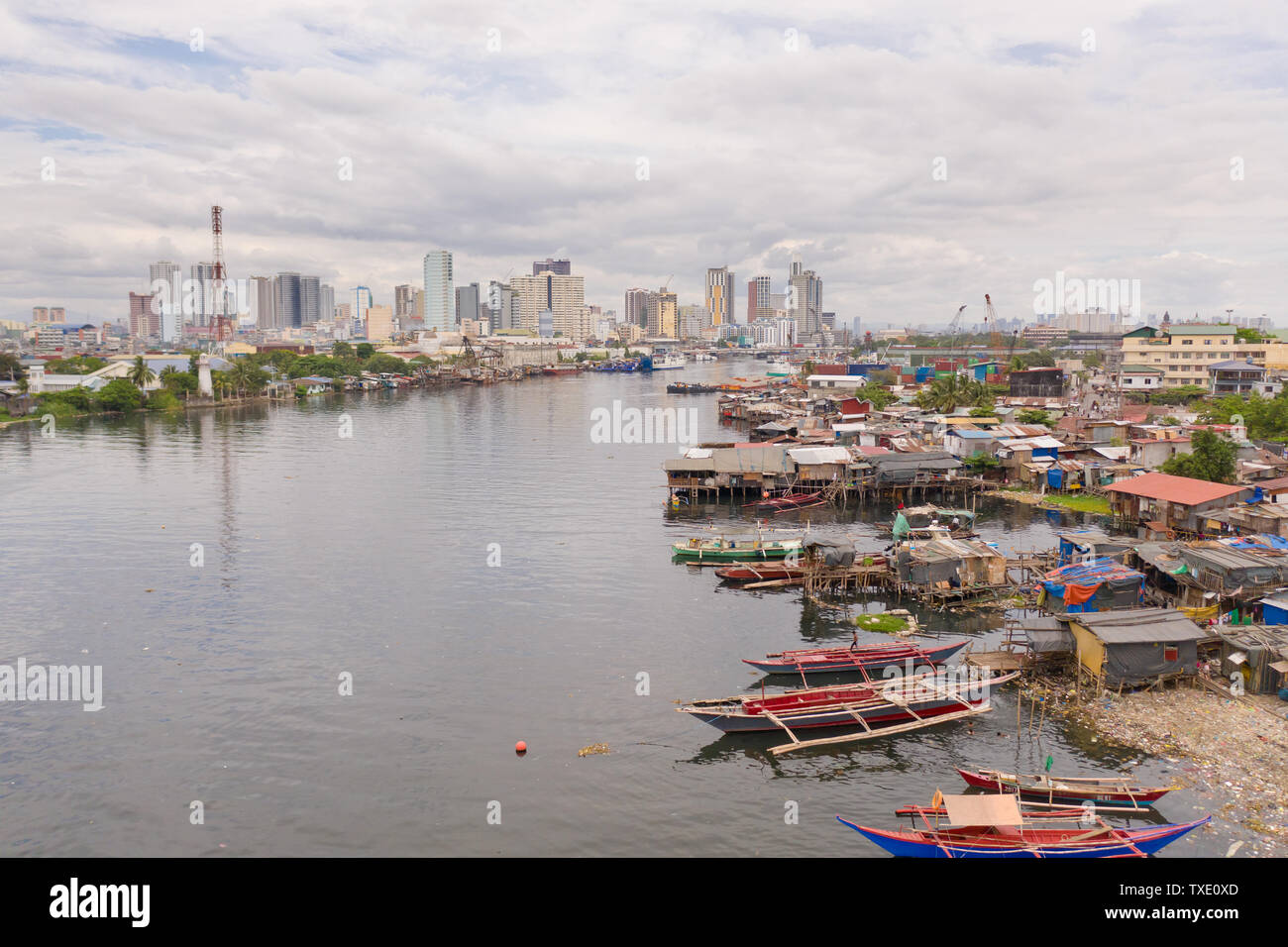 Manila slums on the background of a big city. Houses and boats of the ...