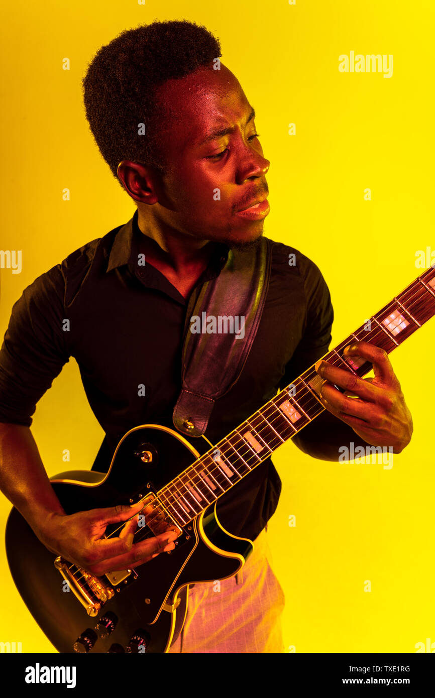 Young african-american musician playing the guitar like a rockstar on ...
