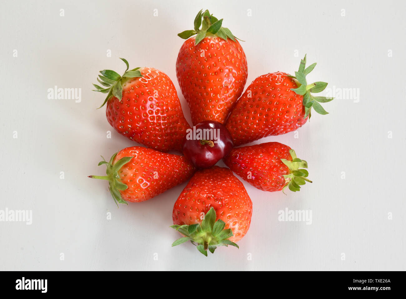 Top view of strawberries with a cherry in the middle on a white ...