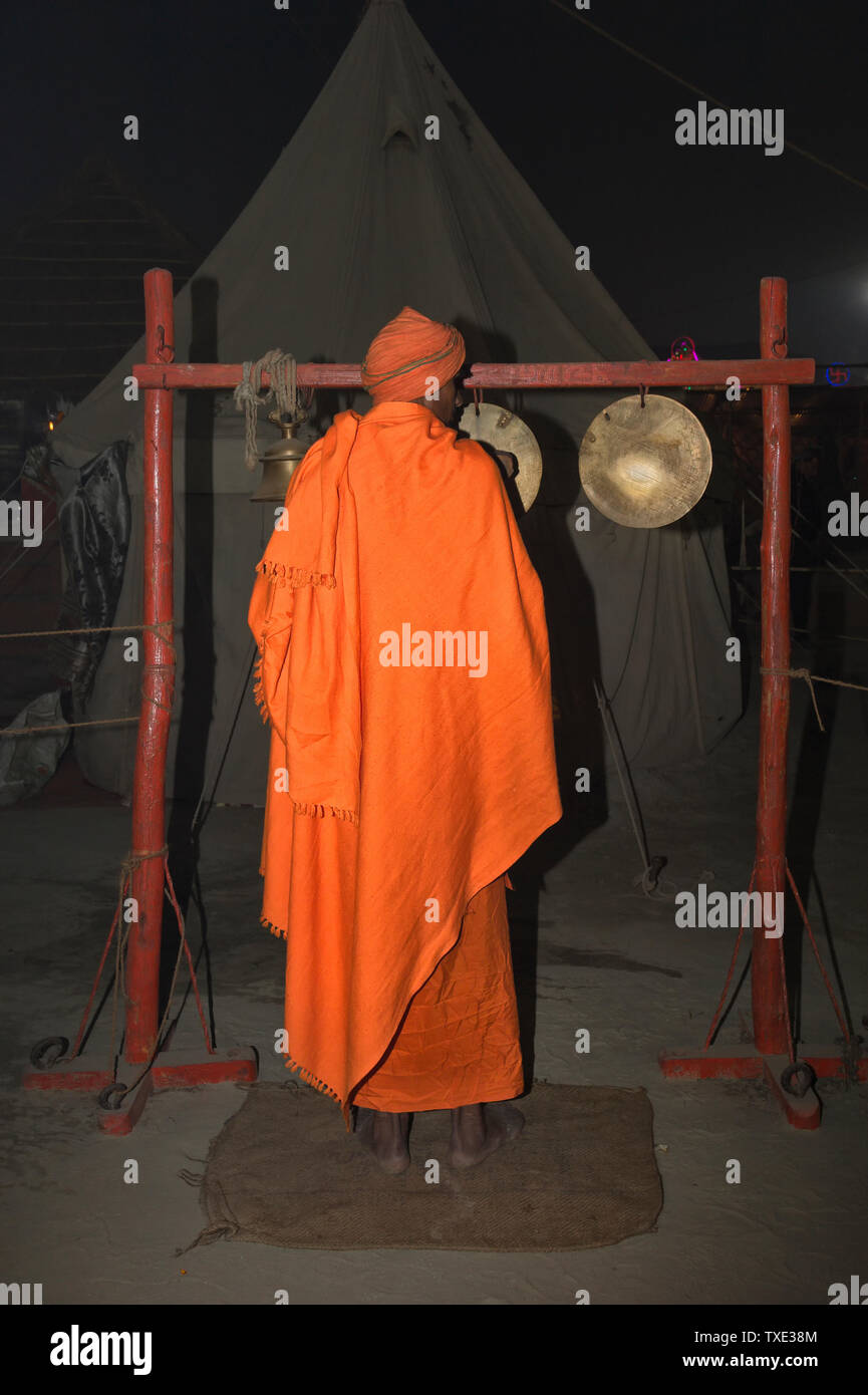 Hindu priest in saffron cloth ringing the bell at night, Allahabad ...