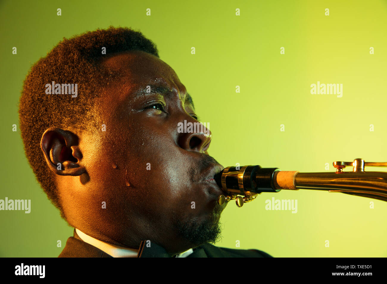 Young african-american jazz musician playing the saxophone on gradient ...