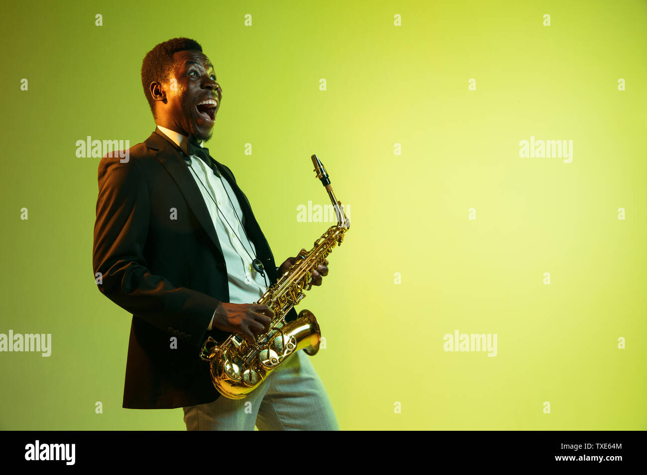 Young african-american jazz musician playing the saxophone on gradient ...