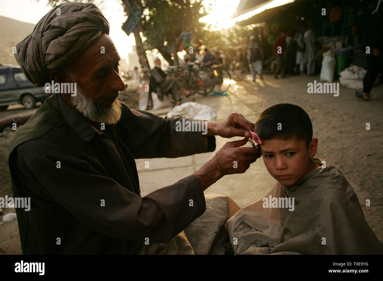 A street barber cuts a boy hair in a bazaar in Kabul, Afghanistan on ...