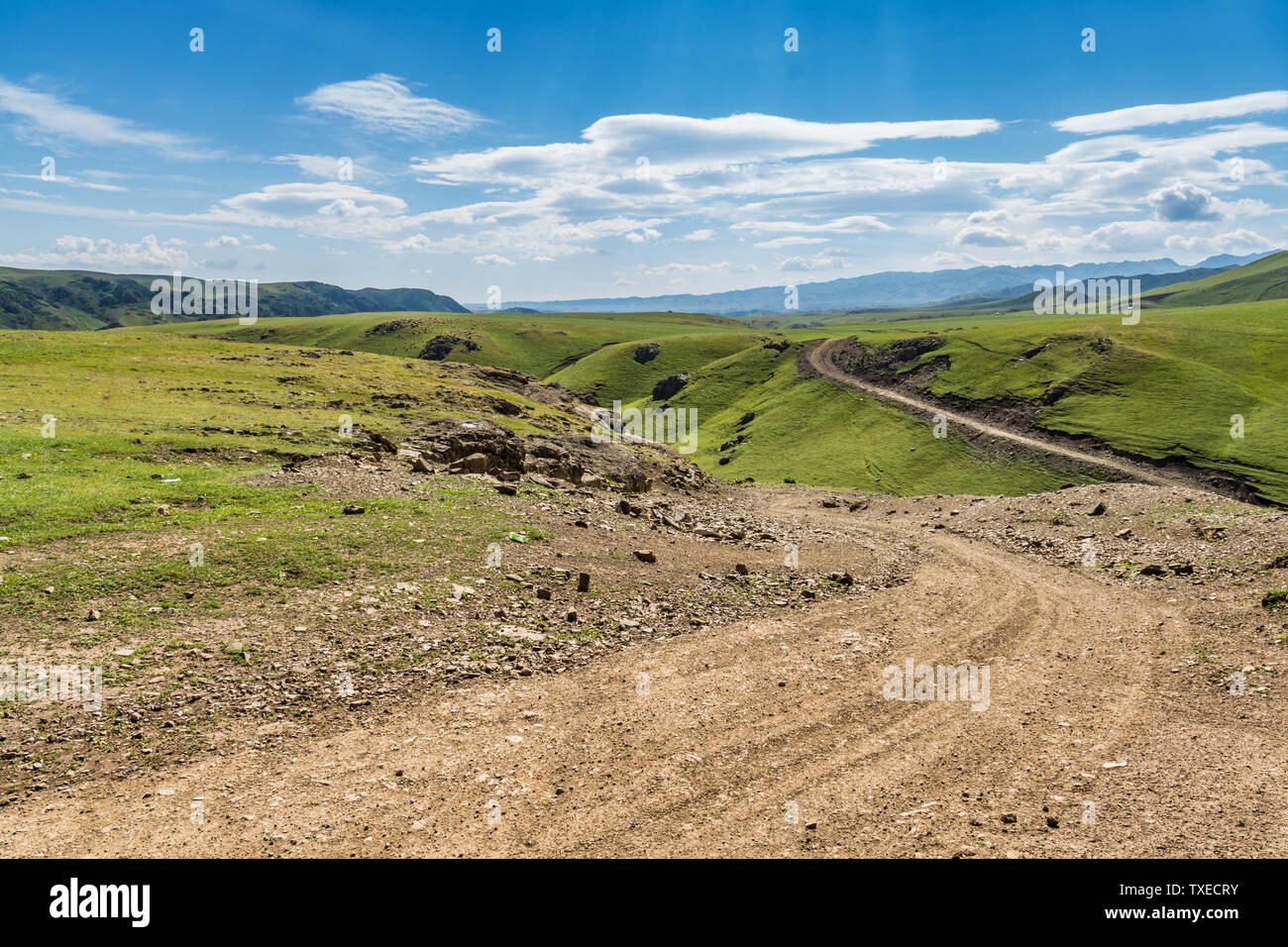 Blue sky and white clouds under hillside prairie sand and gravel ground ...