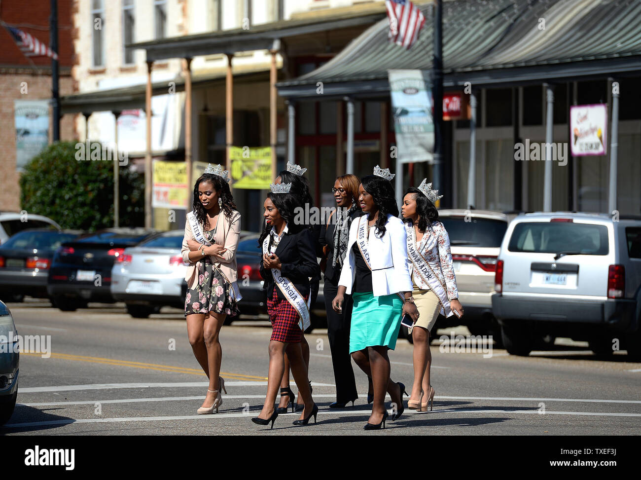 Beauty pageant ambassadors walk across a downtown street during the ...