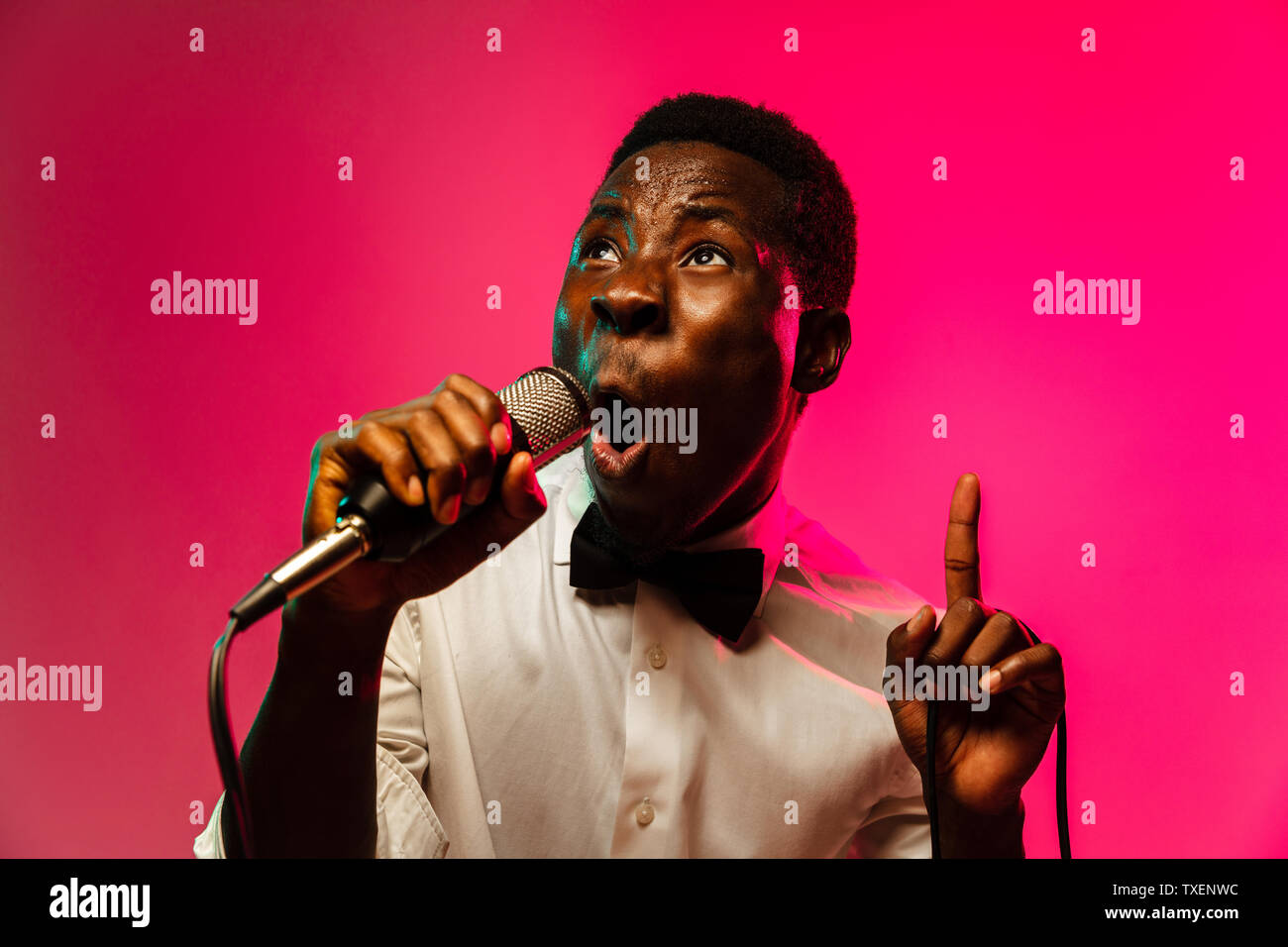 Young african-american jazz musician singing a song on gradient pink ...