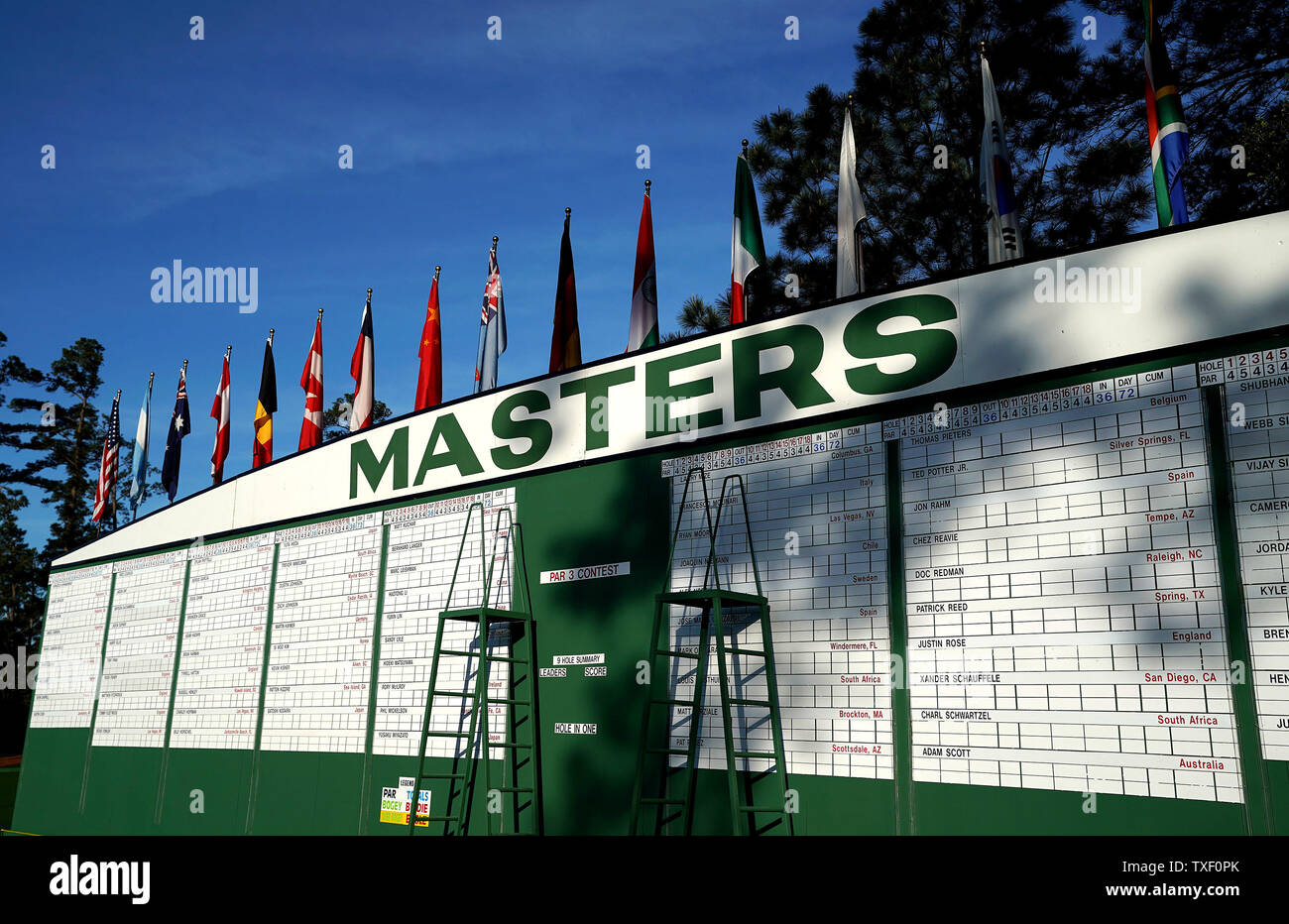 Patrons take photos in front of the scoreboard during a practice round ...