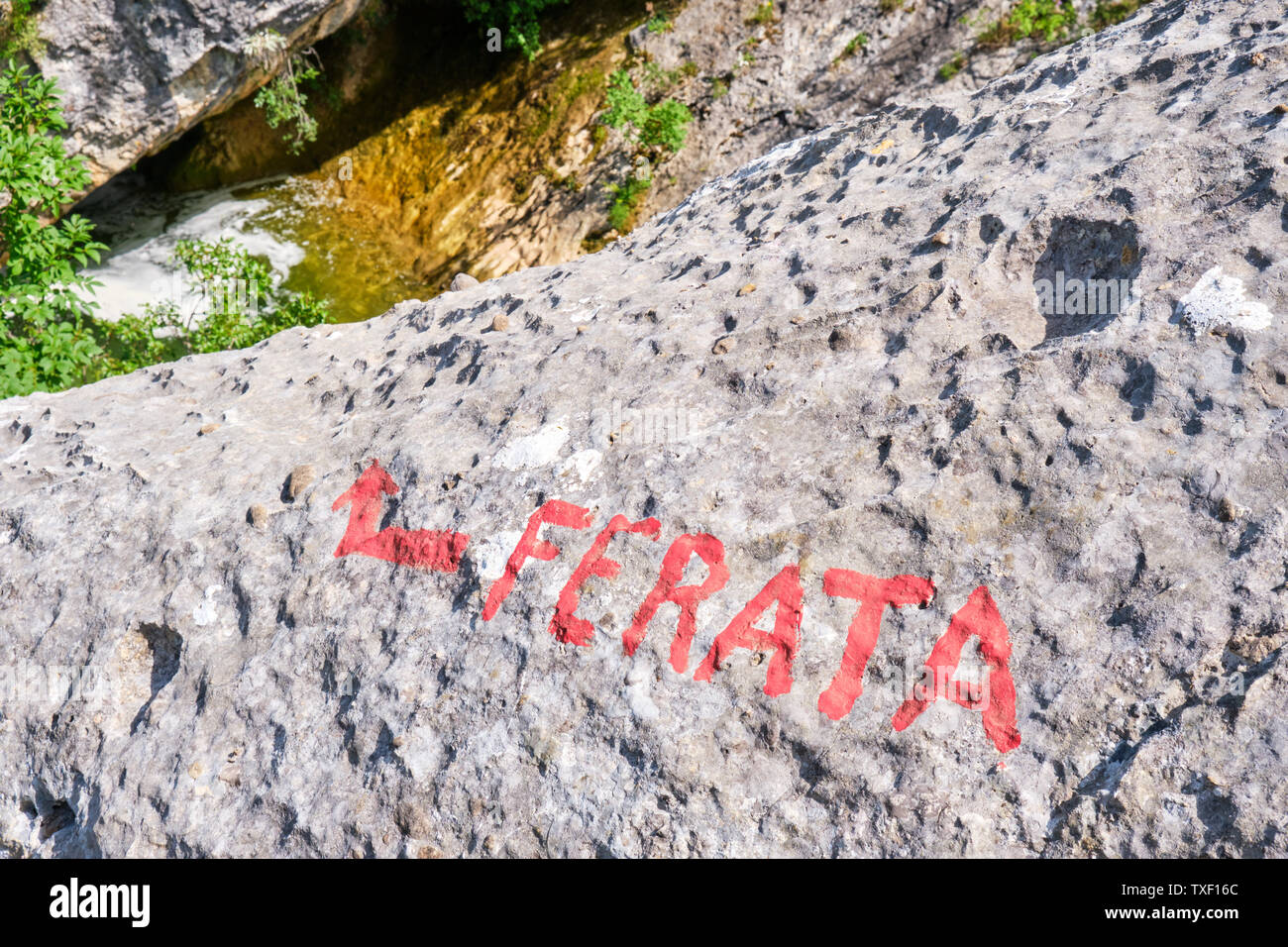 The word ferata - (via) ferrata misspelled - written in red on a rock ...