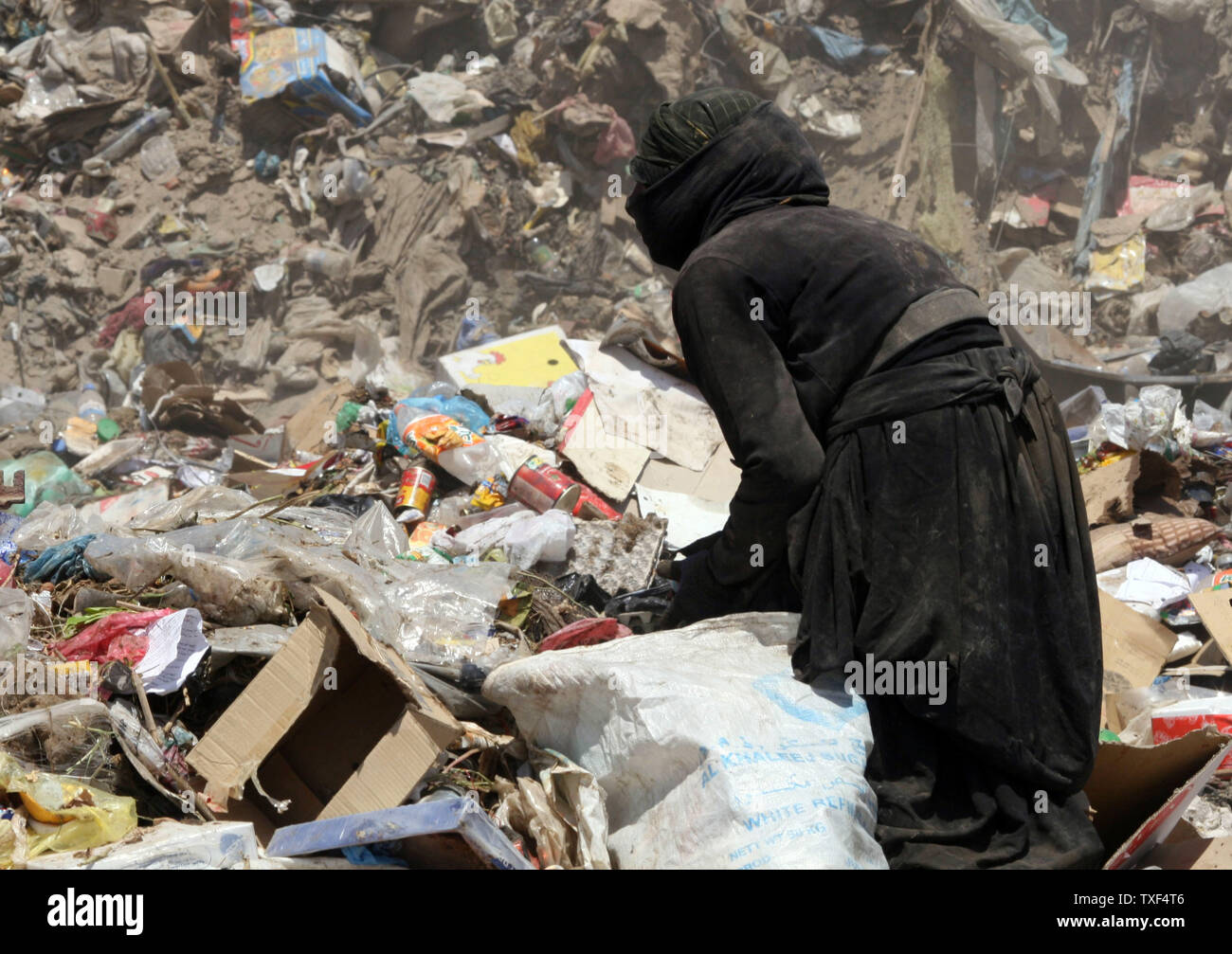 Iraqis rummage through piles of garbage at a dump site in Baghdad on ...