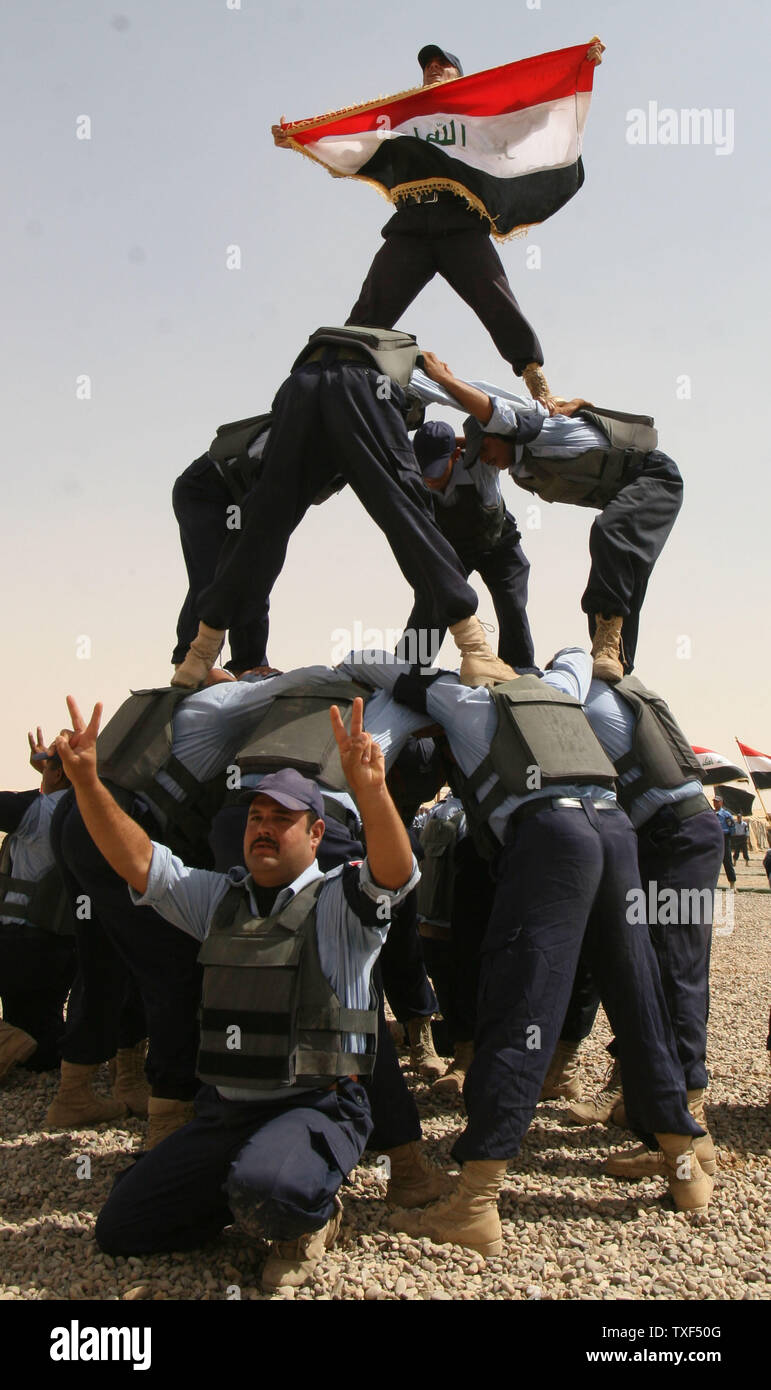 An Iraqi police cadet holds an Iraqi flag on top of a human pyramid ...