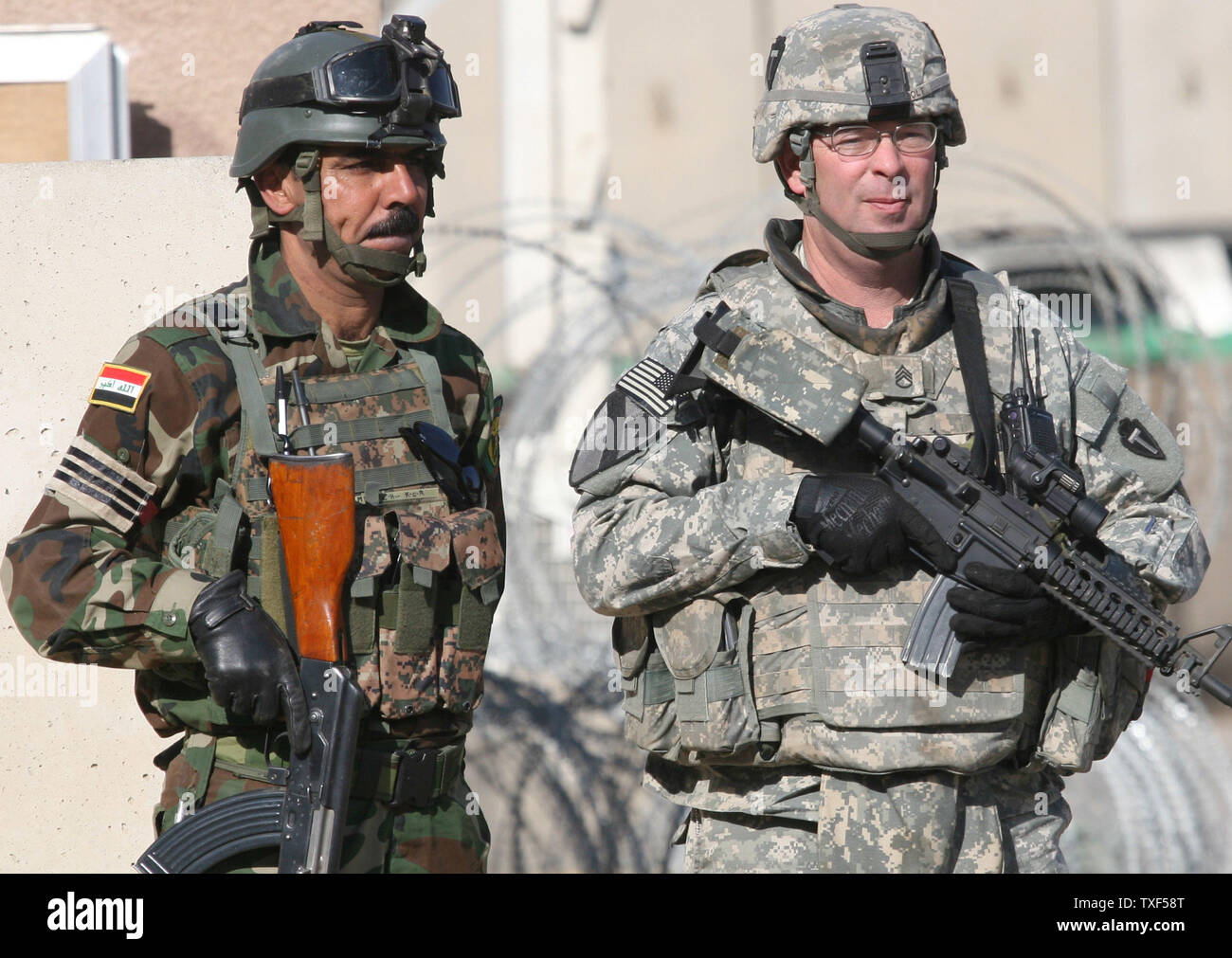 Iraqi (L) and American soldiers stands guard during a handover ceremony ...