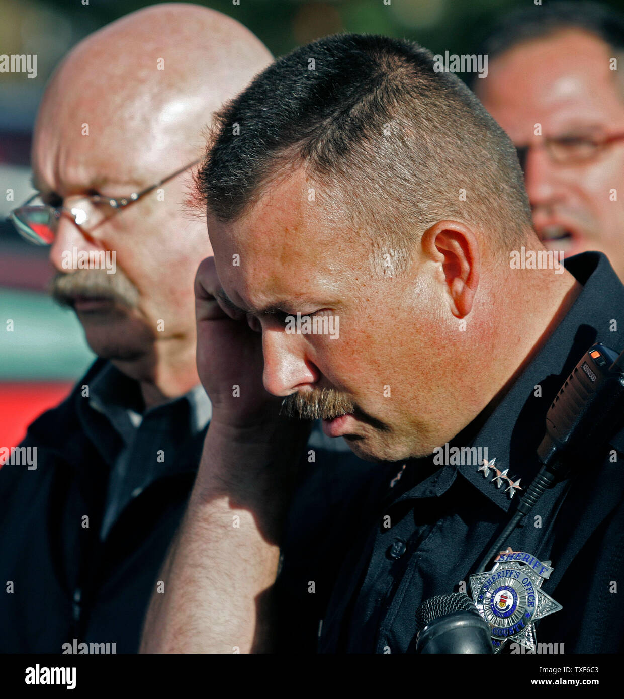 Park County Sheriff Fred Wegener (C) with head bowed talks in a broken ...