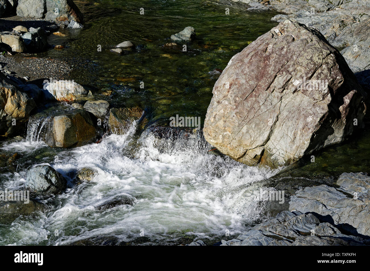 The river flows around a large boulder Stock Photo - Alamy