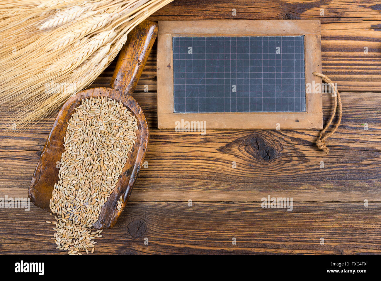 An old slate board, a flour shovel with grain and ears of grain lie on ...